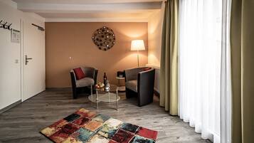 Uma sala de estar com sofá, poltrona, mesa de centro e um tapete colorido.