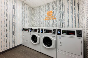 Uma lavanderia com várias máquinas de lavar e uma parede com um padrão de pontos azuis.