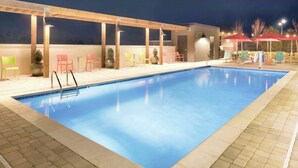 Piscina com deck de madeira e área de estar ao ar livre.