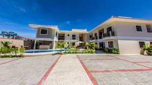 Um hotel com piscina, várias varandas e um pátio pavimentado.