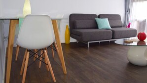 Uma sala moderna com um sofá, uma mesa de jantar com cadeiras e uma mesa de centro de vidro.