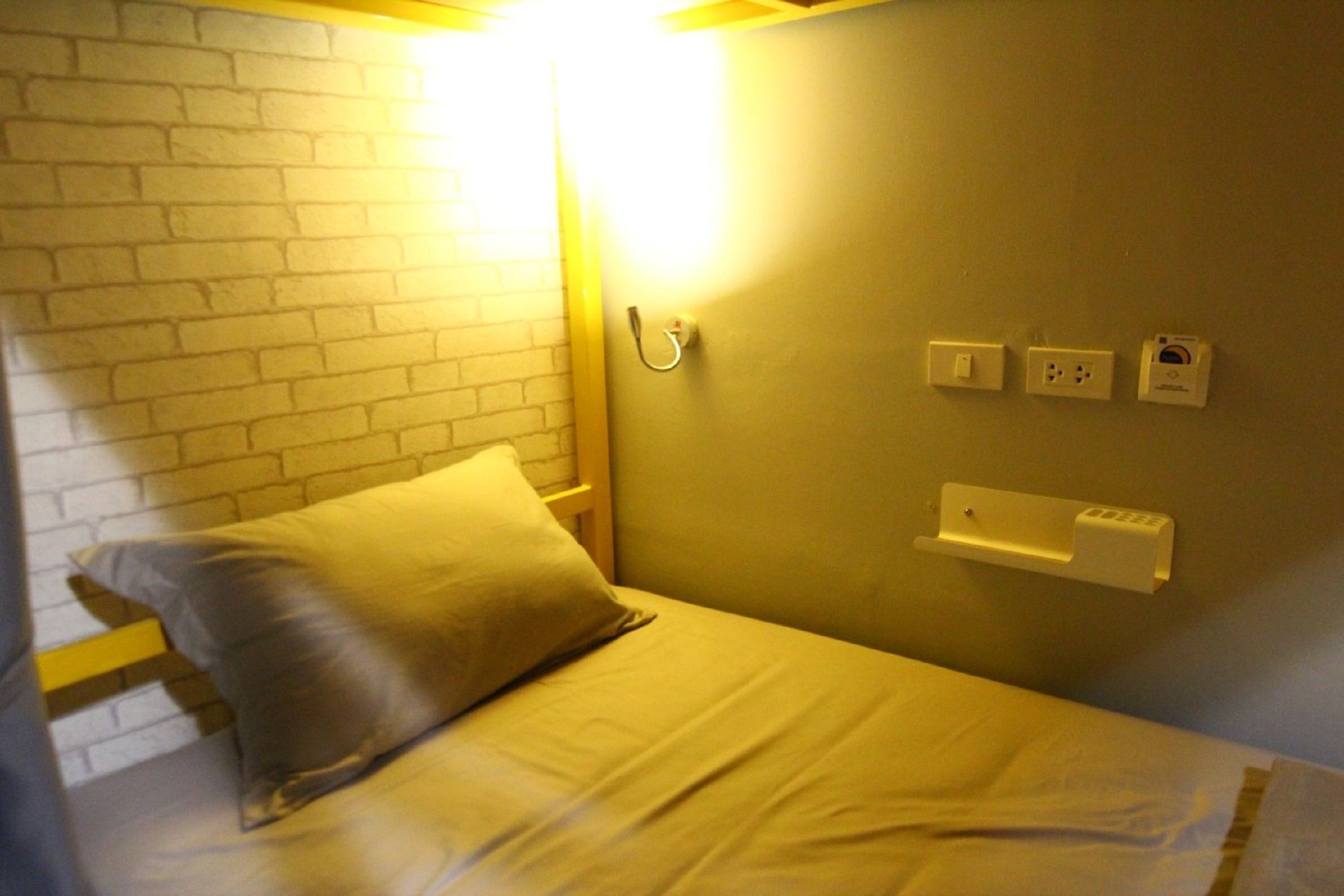 Uma cama de solteiro com um travesseiro, uma tomada e um ponto de energia.