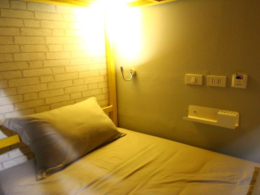 Uma cama de solteiro com um travesseiro, uma tomada e um ponto de energia.