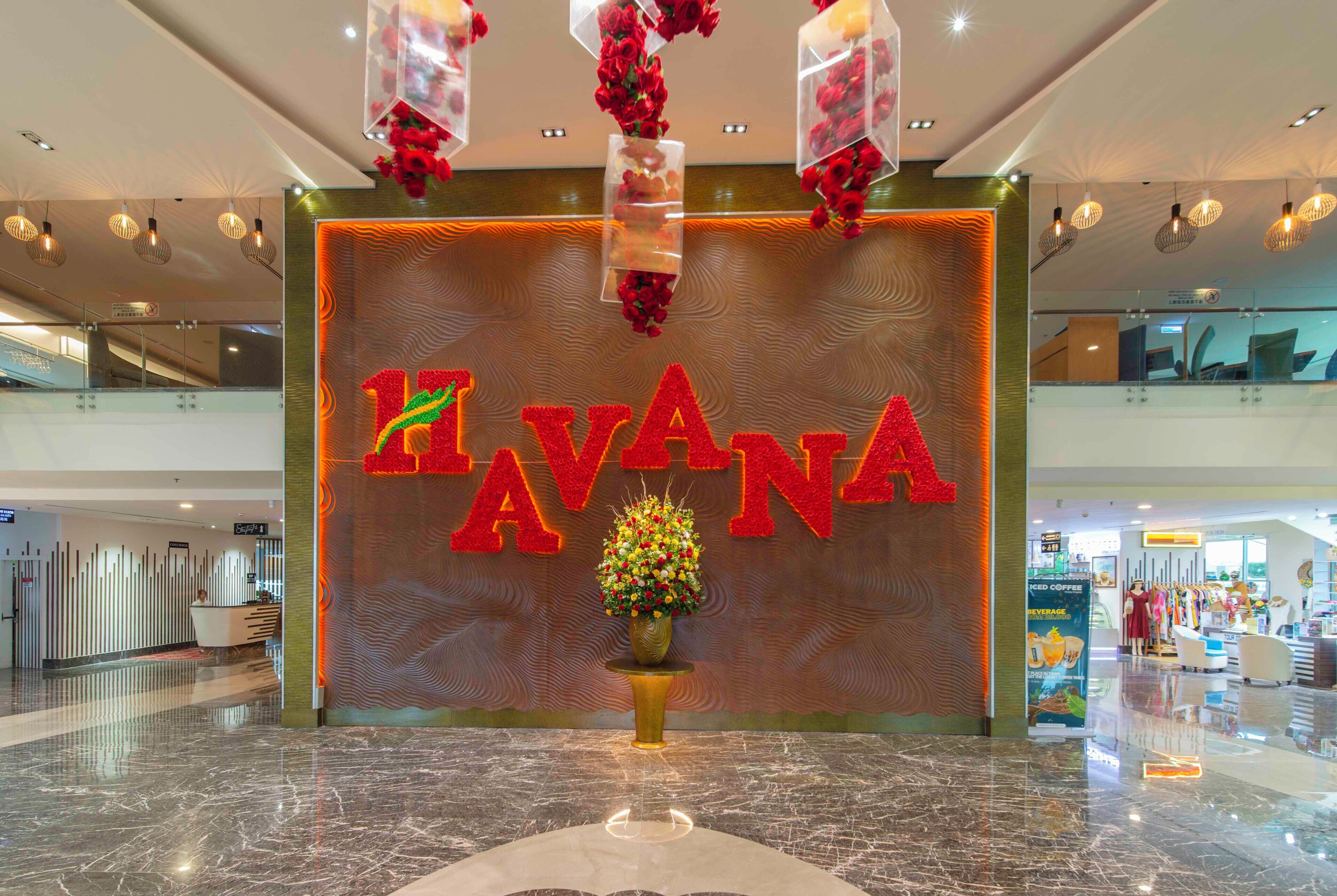 Um saguão de hotel com uma grande placa com a inscrição "HAVANA" e um arranjo floral decorativo.
