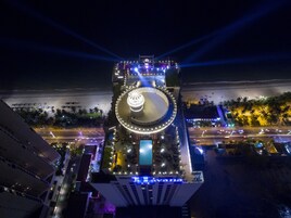 Um hotel moderno com um átrio circular, vários andares e vista para o horizonte da cidade.