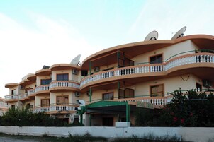 Um edifício com vários andares, varandas, antenas parabólicas e uma placa com a inscrição 'POOL TABLE'.