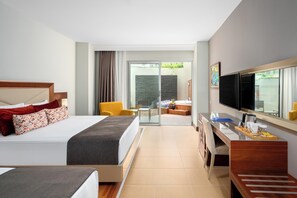 Quarto de hotel com uma cama, uma escrivaninha, uma televisão e uma porta de vidro deslizante para área externa.