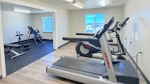 Uma academia moderna com equipamentos de cardio, um espelho grande e janelas amplas com vista.