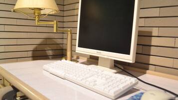 Uma mesa de computador com teclado branco, monitor e rato.