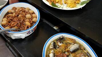 Uma mesa de jantar com diversos pratos, incluindo uma tigela de macarrão, um prato de comida frita e uma tigela de sopa.