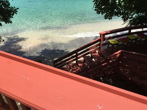 Uma escada de madeira leva a uma praia com águas turquesa cristalinas.