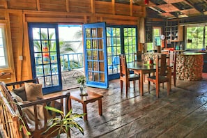 Uma cabana de madeira com área de refeições, portas abertas para uma varanda e cozinha.