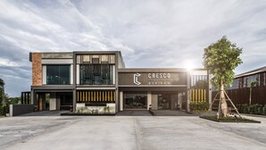 Um edifício moderno de hotel com uma placa em destaque que diz "CRESCO HOTEL BURIRAM".