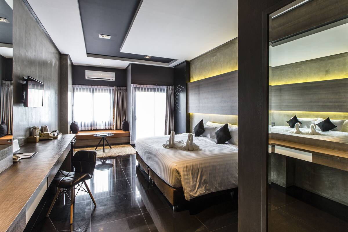 Quarto de hotel moderno com uma cama grande, uma escrivaninha e um espaço de estar.