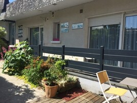 Um edifício residencial com varanda, plantas em vasos e uma cadeira.