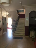 Uma escada com corrimão de metal que leva a um nível superior. Há um tapete no final da escada.
