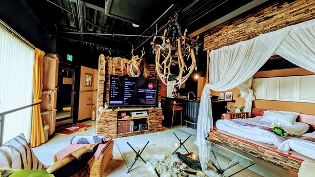 Quarto com cama, televisão, parede de madeira e lustre.