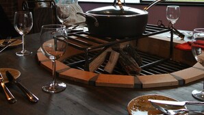 Uma sala de jantar com vista para montanhas, mesa posta com talheres e copos de vinho, e design de cadeira exclusivo.