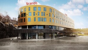 Um edifício moderno com fachada amarela e várias janelas, identificado como "Scandic".