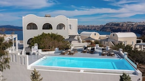 Um hotel moderno com piscina, área externa para sentar e vista para o mar e montanhas.