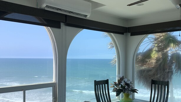 Quarto com vista para o oceano, ventoinha no teto e uma mesa com cadeiras.