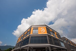 Um edifício moderno com uma placa grande 'Smith', janelas amplas e um céu claro com nuvens.