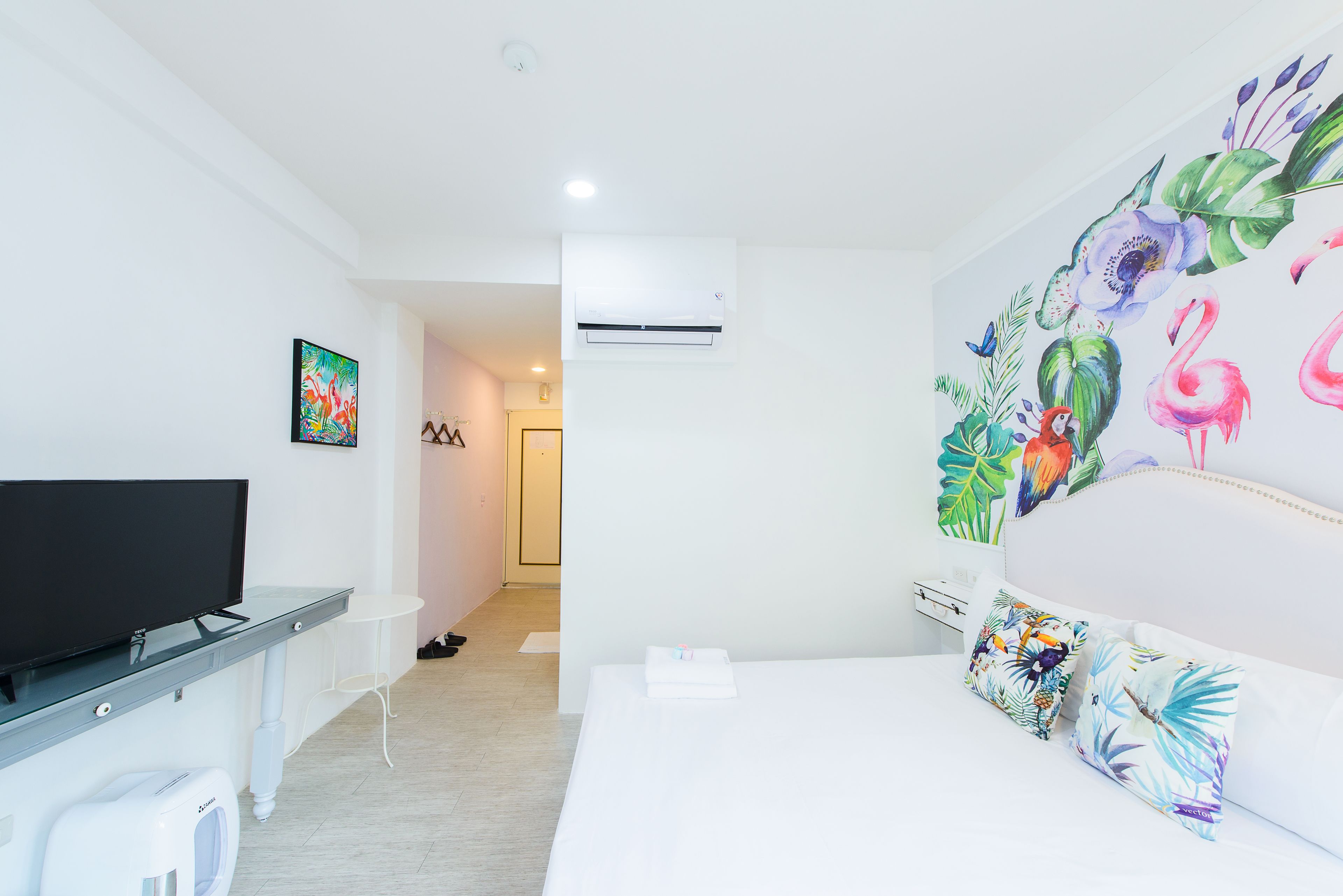 Quarto de hotel com uma cama, televisão, ar condicionado fixado na parede e banheiro ao fundo.