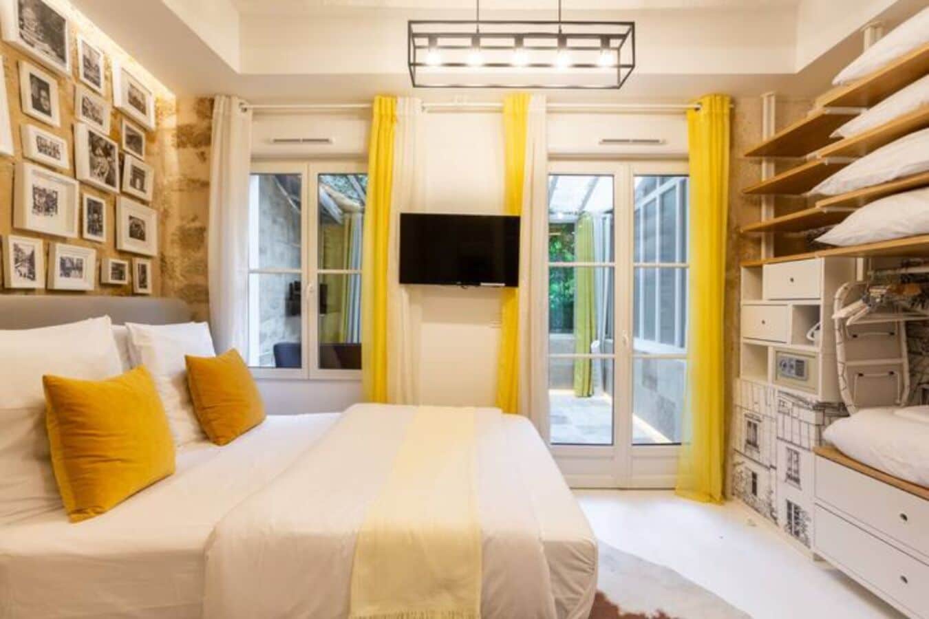 Quarto com cama, televisão, janela com cortinas e guarda-roupa.