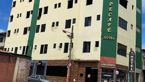 Um hotel de vários andares com fachada verde e branca, várias janelas e uma entrada visível.