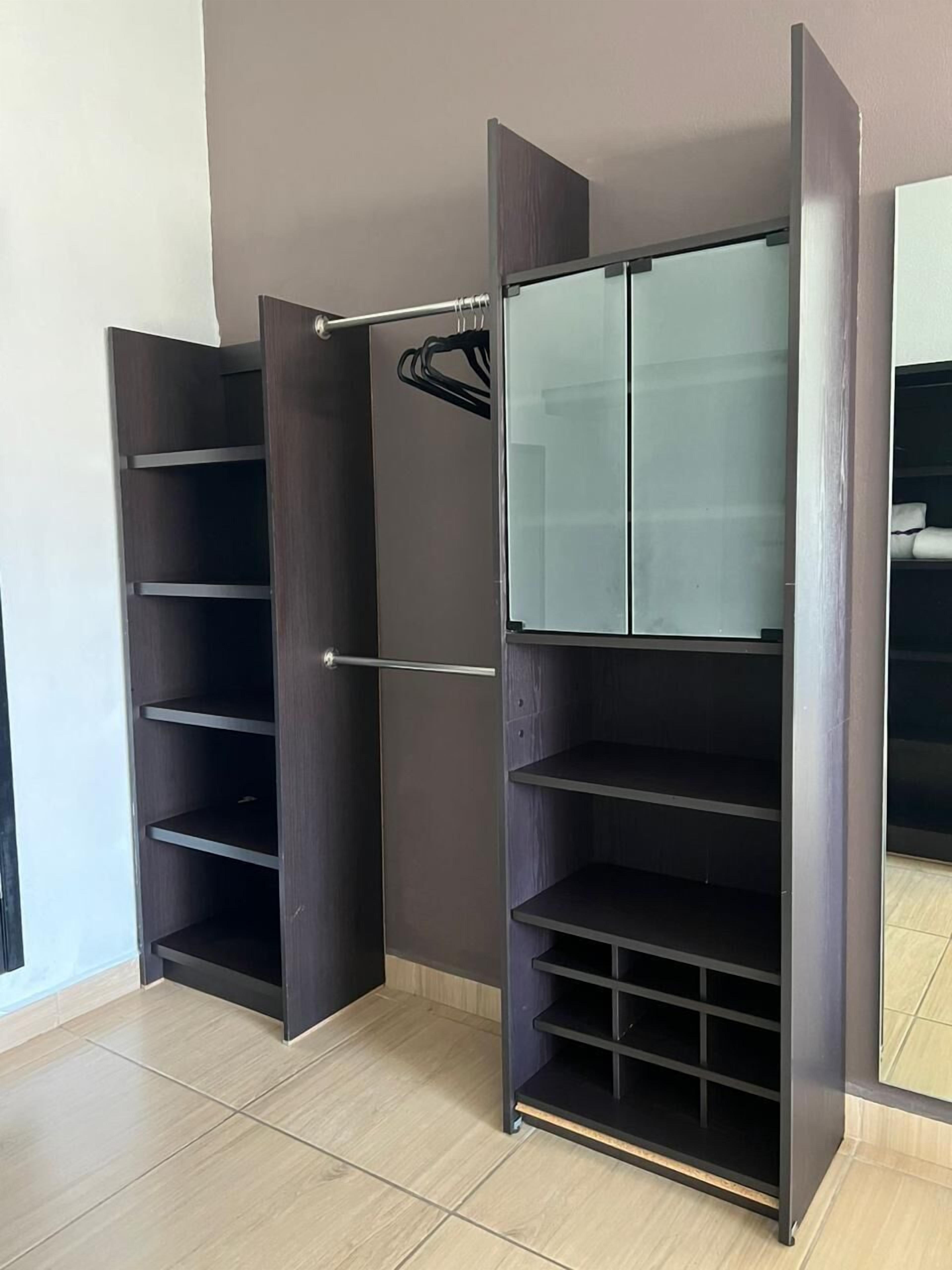Guarda-roupa moderno com várias prateleiras e um espelho.