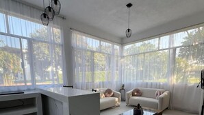 Uma sala de estar ampla com um conjunto de sofá branco, uma mesa de centro e uma parede em mármore.