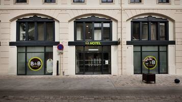 Fachada de hotel com estilo arquitetônico clássico, apresentando janelas em arco e uma entrada imponente.