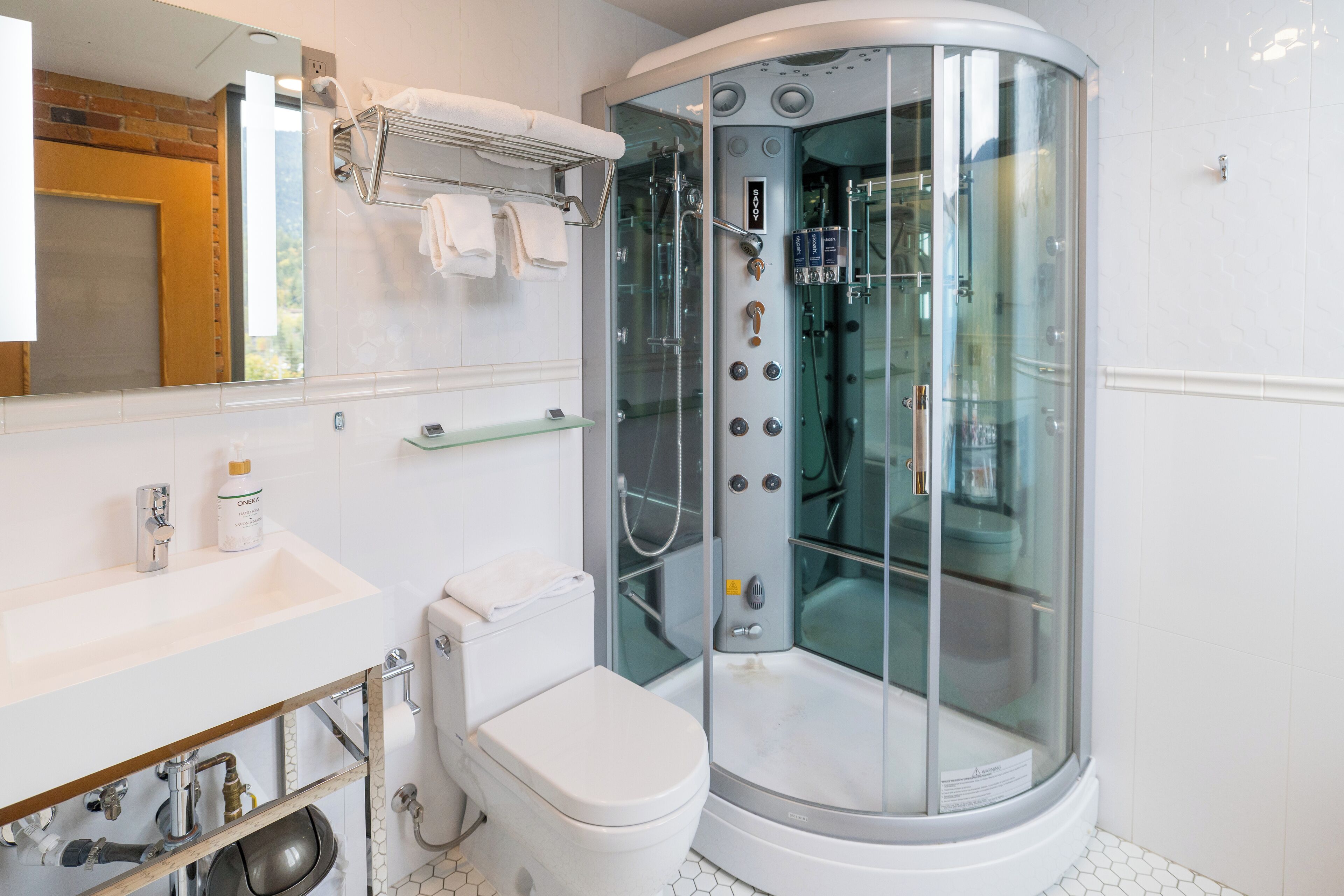 Uma casa de banho moderna com cabine de duche em vidro, lavatório branco e sanita.