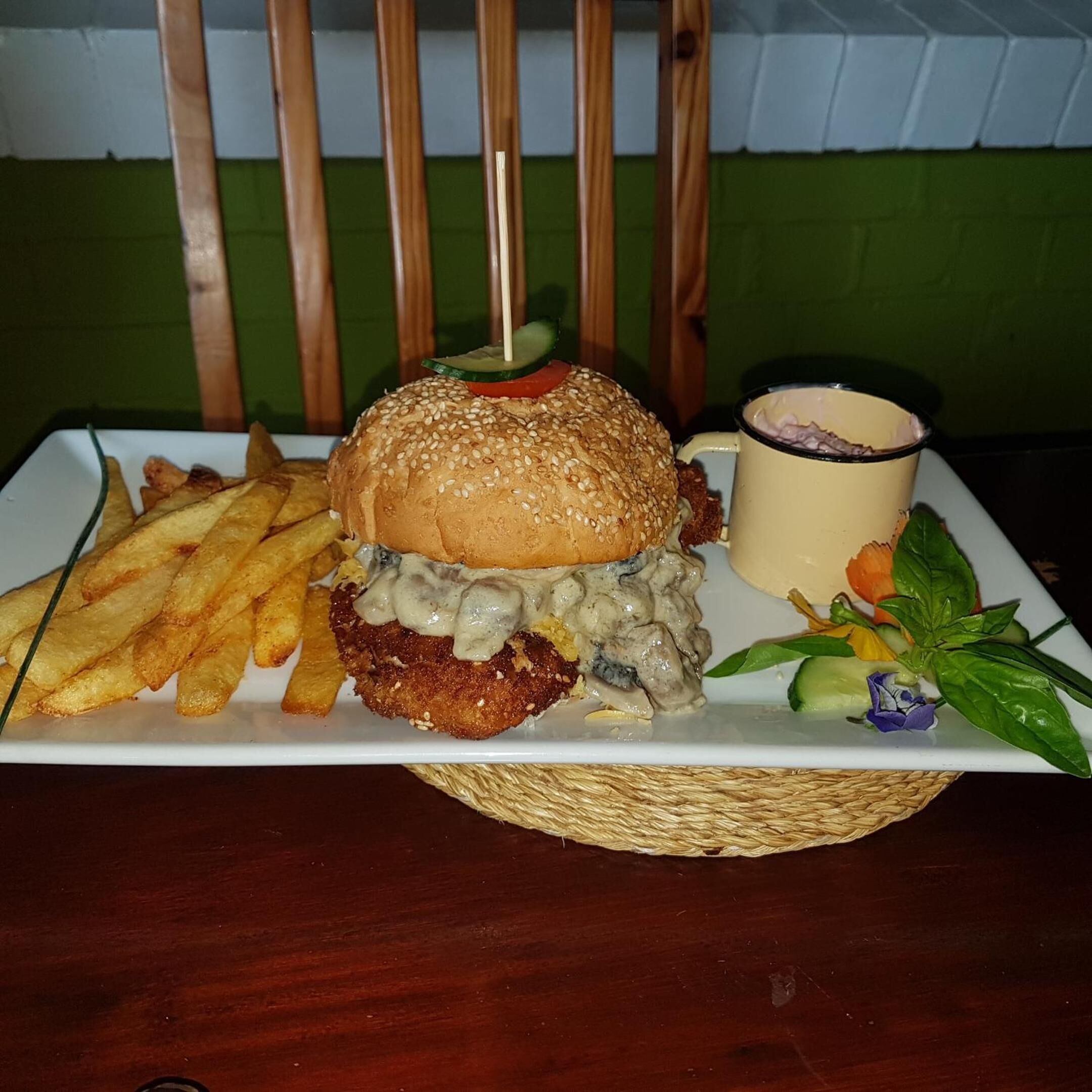 Um prato com um hambúrguer, batatas fritas e uma sopa.