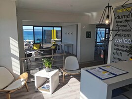 Um espaço de escritório moderno com vista para o mar, uma receção e áreas de estar.