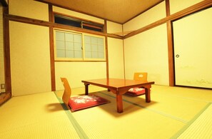 Um quarto japonês tradicional com tatames, uma mesa de madeira baixa e uma porta deslizante.