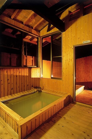 Uma cabana de madeira com hidromassagem, paredes de madeira e uma janela grande.