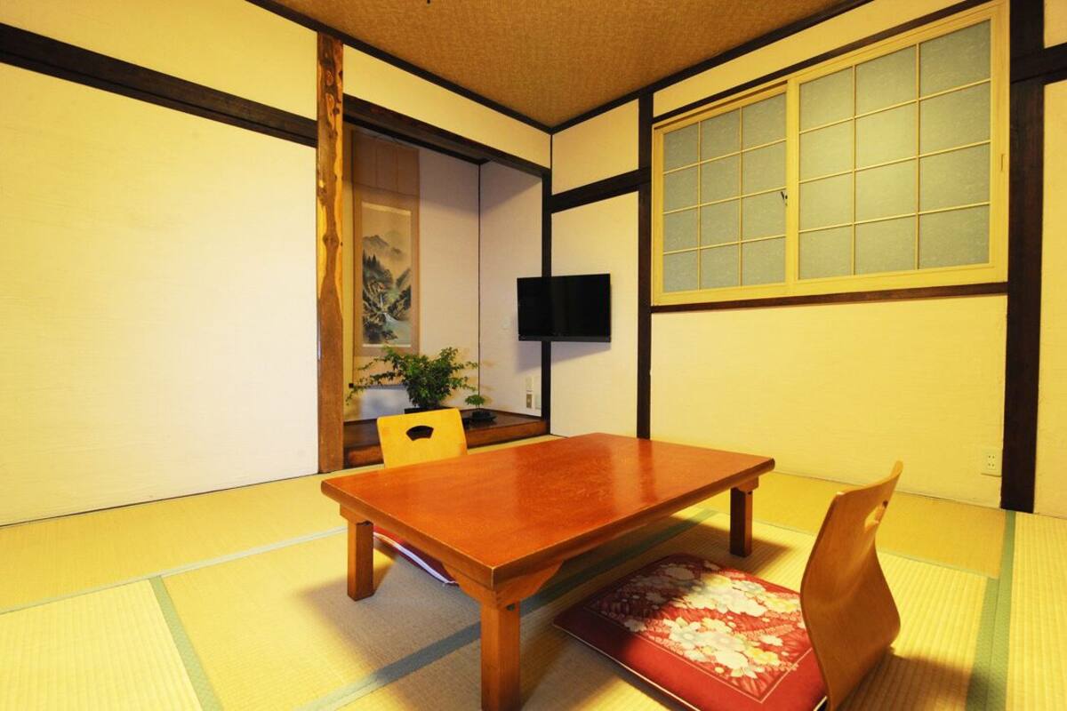 Um quarto japonês tradicional com tatames, uma mesa de madeira baixa e uma porta de correr.
