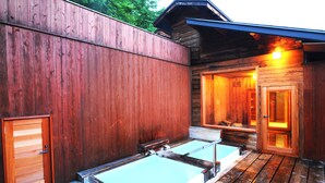 Uma cabana de madeira com sauna, um deck de madeira e uma grande porta de madeira.