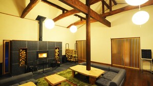 Uma sala de estar acolhedora com lareira, vigas de madeira e um tapete verde.
