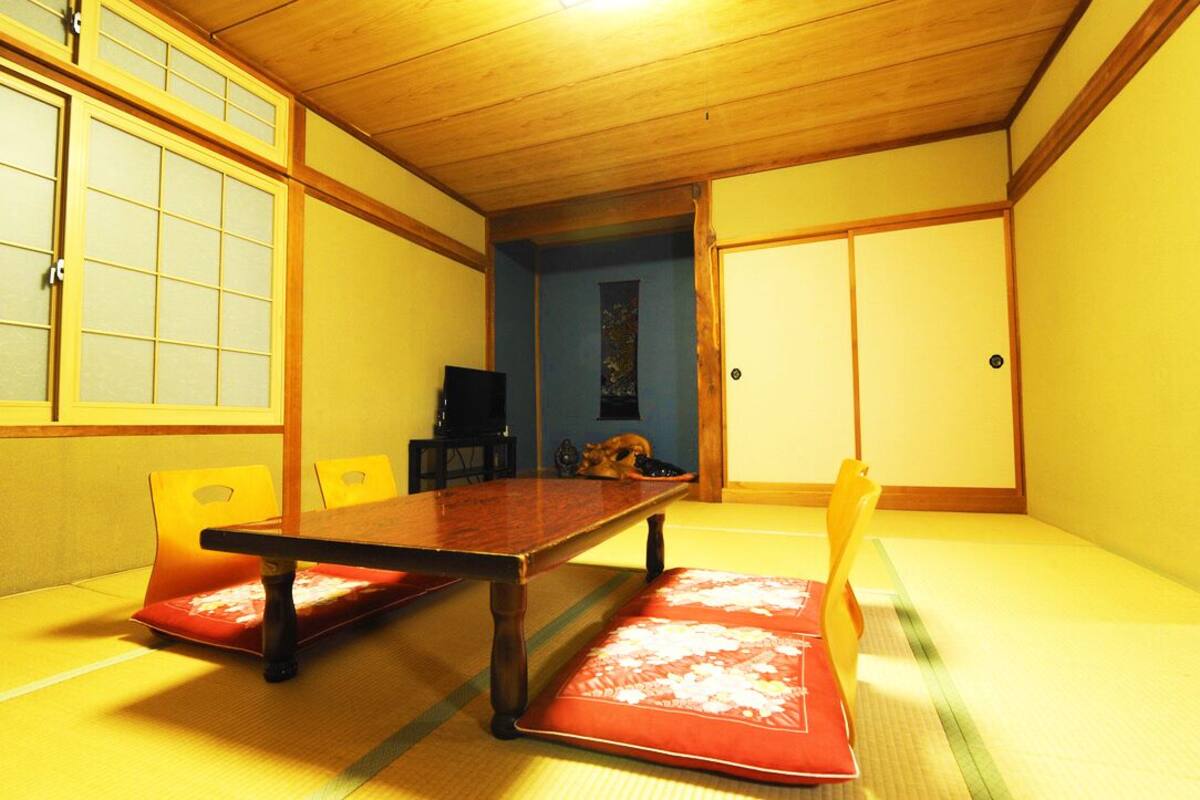 Um quarto japonês tradicional com tatames, uma mesa de madeira baixa e portas deslizantes.