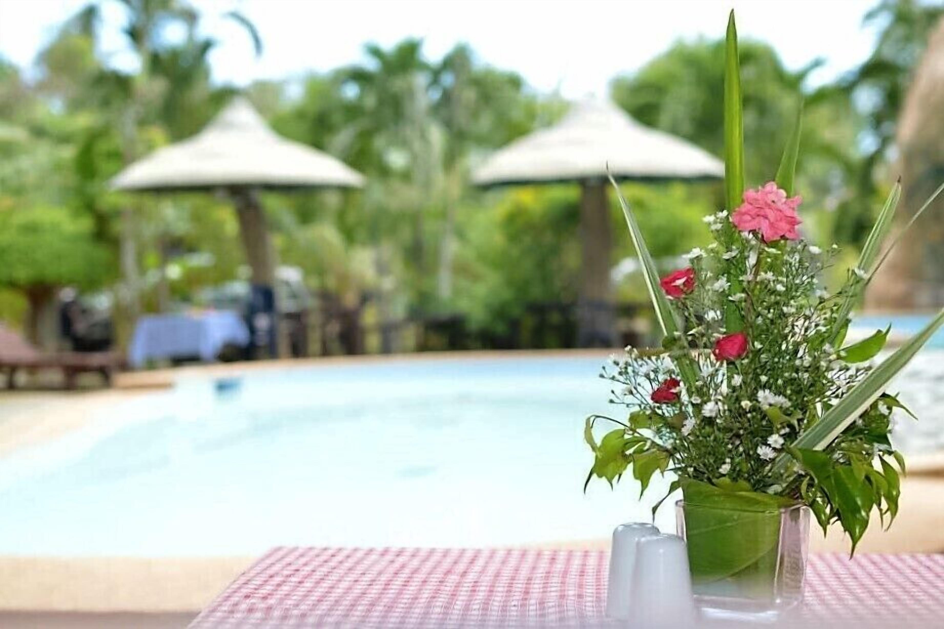 Mesa à beira da piscina com arranjo de flores, saleiro e um copo d'água.