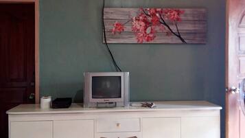 Quarto com teto de madeira, escrivaninha com televisão e pintura pendurada na parede.