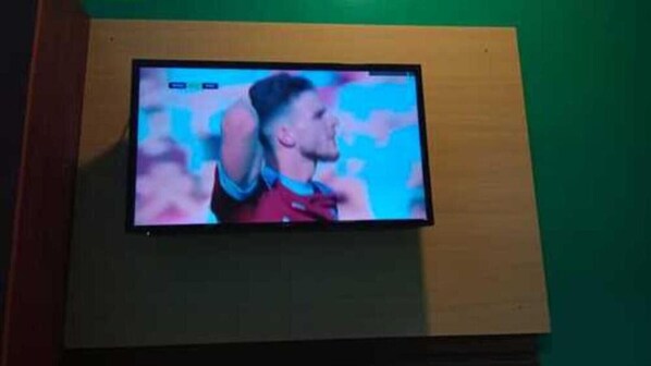 Uma televisão fixada em uma superfície de madeira, com uma parede verde ao fundo.