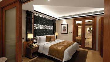 Quarto de hotel moderno com uma cama grande, cabeceira de madeira e vista para um banheiro por uma porta de vidro.