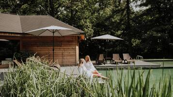 Uma cabana de madeira com piscina, rodeada por vegetação exuberante.