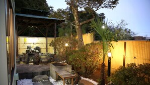 Um jardim japonês tradicional com um caminho de pedra, um banco de madeira e uma cerca de bambu.