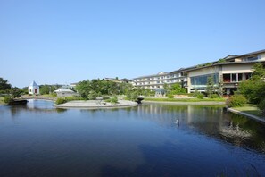 Um lago tranquilo com uma ponte, rodeado por edifícios modernos com varandas e grandes janelas.