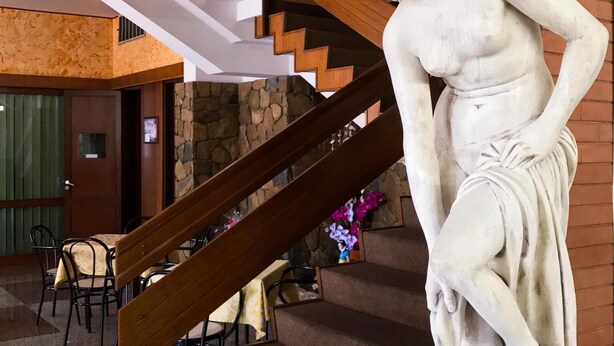 Uma escadaria com uma estátua de mármore branco de uma mulher sentada e um cachorro.