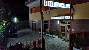 Um hotel chamado "HOTEL SOLE", com uma placa acima da entrada, um portão na entrada e plantas em vasos ao redor do edifício.
